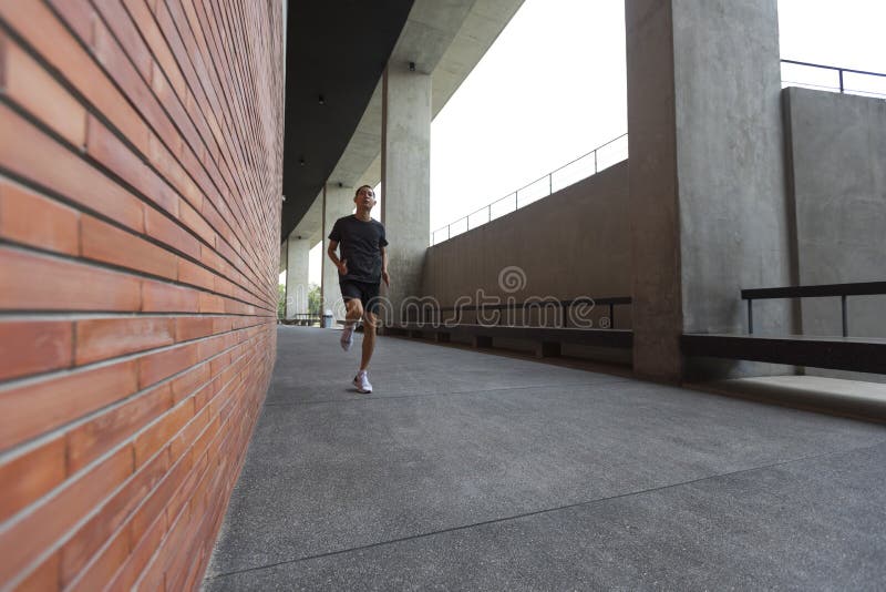Young Athletic Man Running and Training Himself on the Urban Building ...