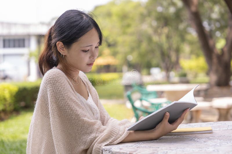 Young Attractive Asian Girl Sitting at Table,concentrate on Reading a ...