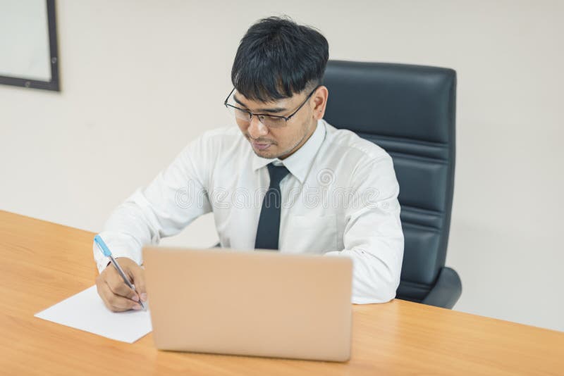 Young Attractive Businessman Thinking, Writing on Paper and Computer ...
