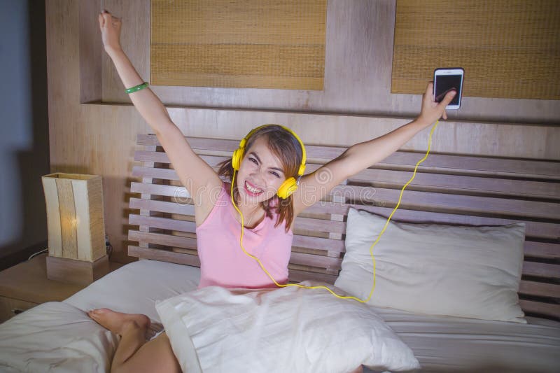 Young Attractive And Happy Woman In Bed With Yellow Headphones