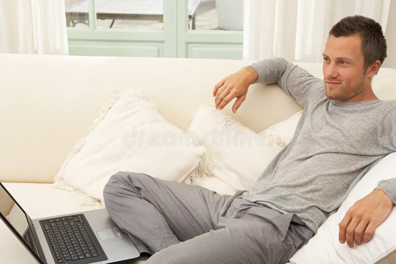 Young Attractive Man on Couch with Laptop at Home. Stock Image - Image ...