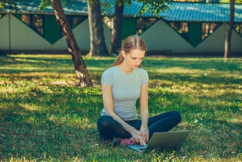 Young Attractive Woman Sitting in a Public Garden while Using Her ...
