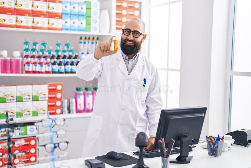 Young Bald Man Pharmacist Using Computer Holding Pills Bottle at ...