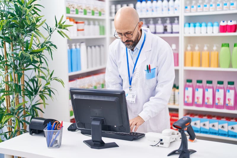 Young Bald Man Pharmacist Using Computer at Pharmacy Stock Image ...