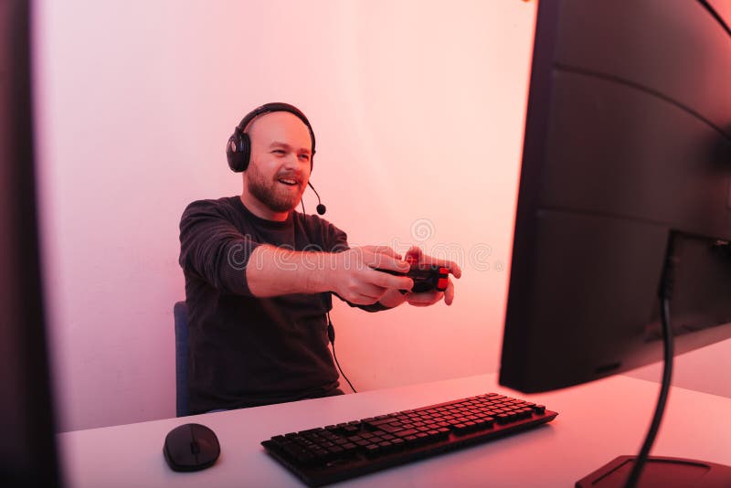 Young Bald Man is Playing with Joystick at the Computer while Wearing ...