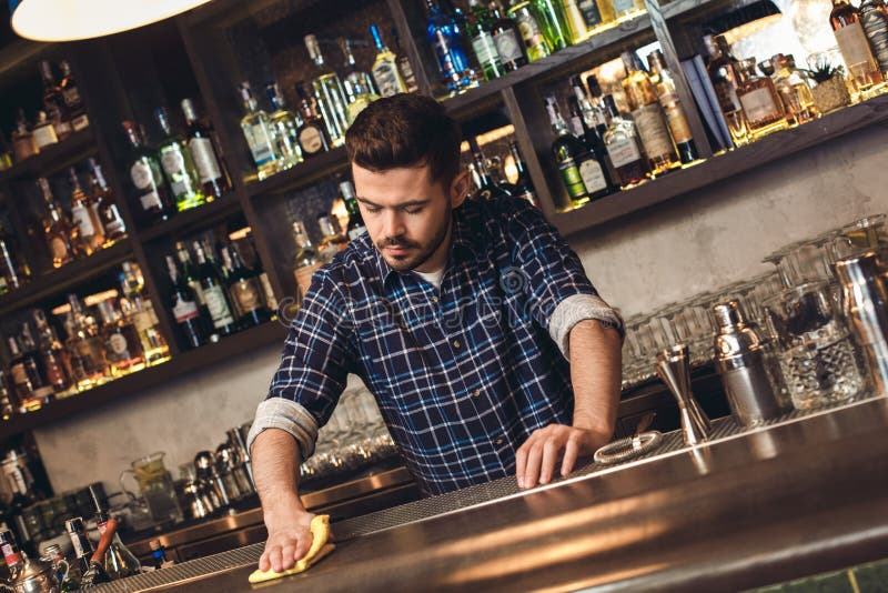 Young Bartender Standing at Bar Cleaning Counter Thoughtful Stock Photo ...
