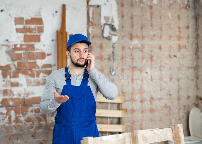 Young Bearded Contractor Talking on Phone at Construction Site Indoors ...