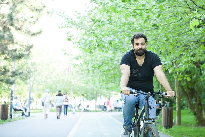 Young Bearded Man Riding a Bicycle in the Park Stock Photo - Image of ...