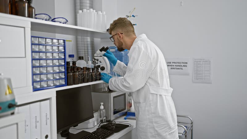 A Young Bearded Scientist Analyzes Samples Using a Microscope in a ...