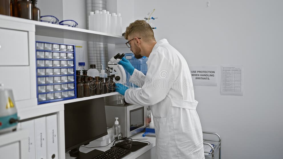 A Young Bearded Scientist Analyzes Samples Using a Microscope in a ...