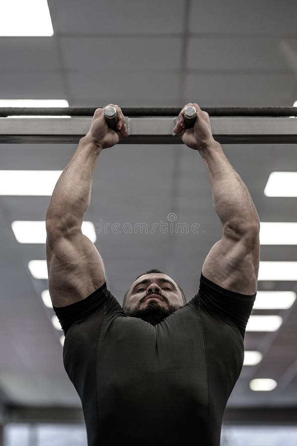 Young Bearded Strong Sport Man in Black Jersey Making Pull-ups Indoors ...
