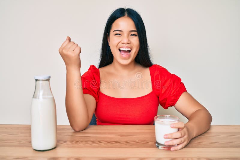 Young Beautiful Asian Girl Drinking A Glass Of Fresh Milk Screaming