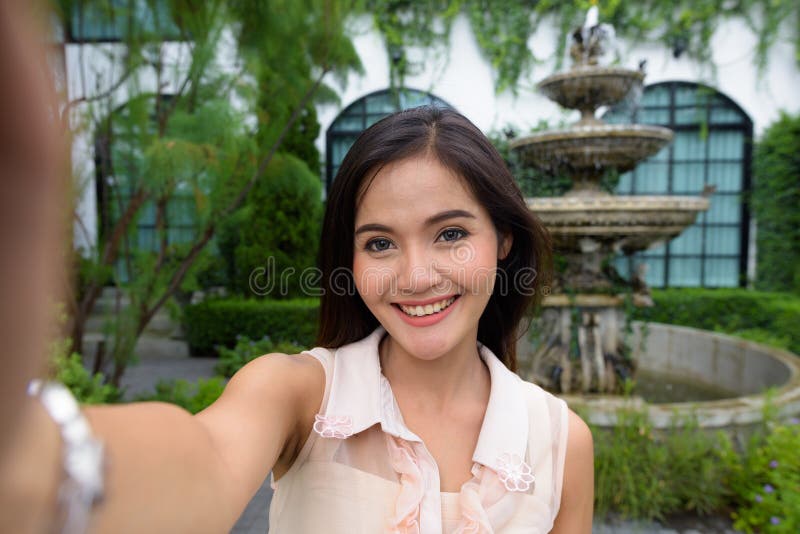 Young Beautiful Asian Woman Taking Selfie While Relaxing At The Stock