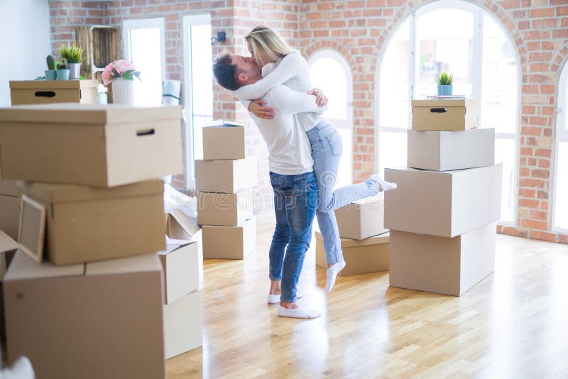 Young Beautiful Couple Hugging at New Home Around Cardboard Boxes Stock ...
