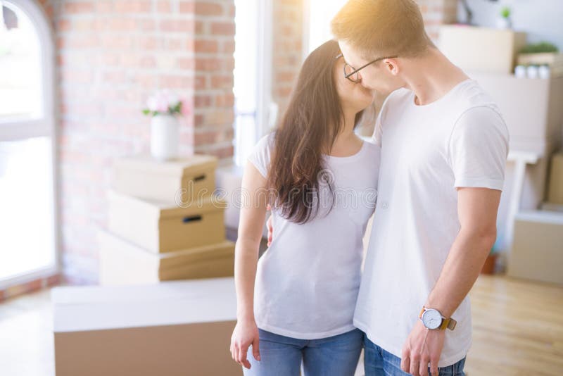 Young Beautiful Couple Kissing Wearing Glasses Standing At New Home