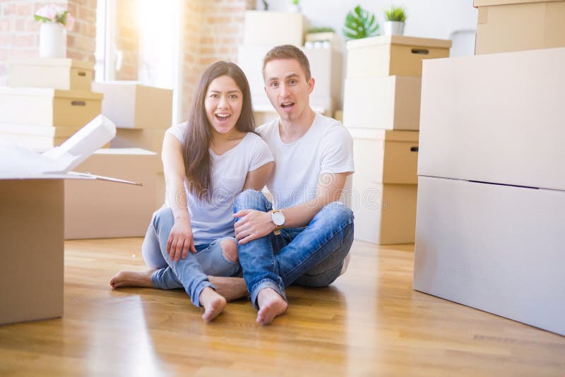 Young Beautiful Couple Sitting On The Floor At New Home Around