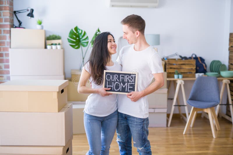 Young Beautiful Couple Standing On The Floor Holding Blackboard With