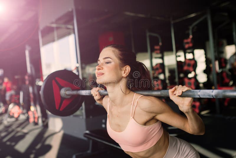 A Young and Beautiful Female Trains with a Barbell in the Gym. Posing ...