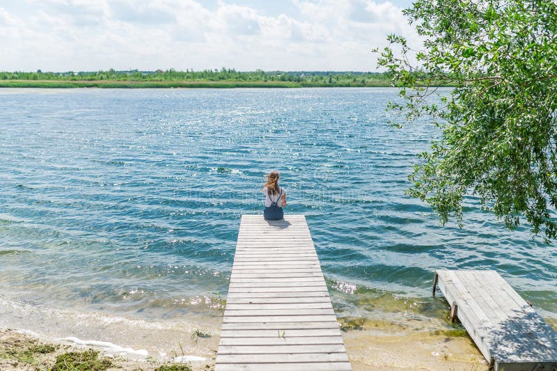 Young Beautiful Girl Sitting on Jetty River on Background Stock Image ...