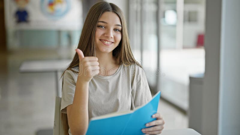 Young Beautiful Girl Student Reading Book Doing Thumb Up Gesture ...