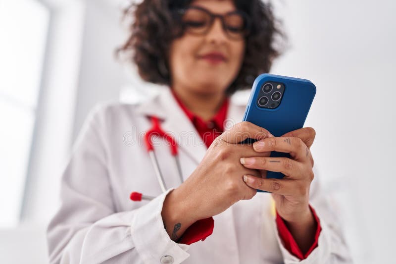 Young Beautiful Hispanic Woman Doctor Using Smartphone Standing at ... Young Beautiful Hispanic Woman Doctor Using Smartphone Standing at ...
