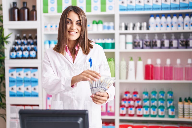 Young Beautiful Hispanic Woman Pharmacist Counting Dollars Using ...