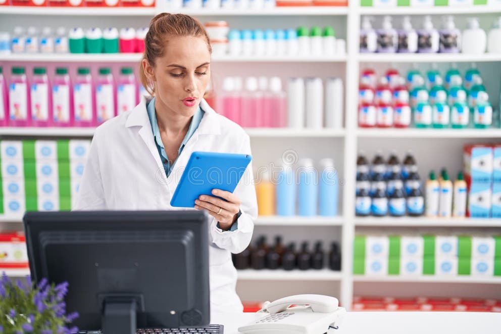 Young Beautiful Hispanic Woman Pharmacist Using Computer and Touchpad ...