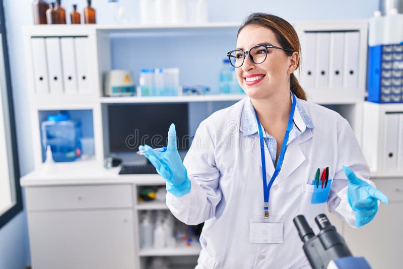 Young Beautiful Hispanic Woman Scientist Using Microscope Speaking at ...