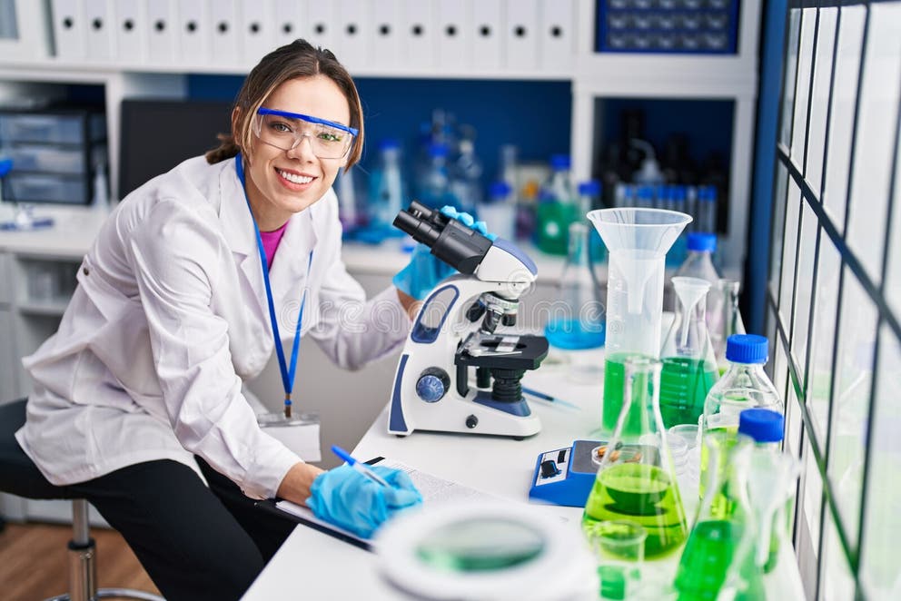 Young Beautiful Hispanic Woman Scientist Using Microscope Writing on ...