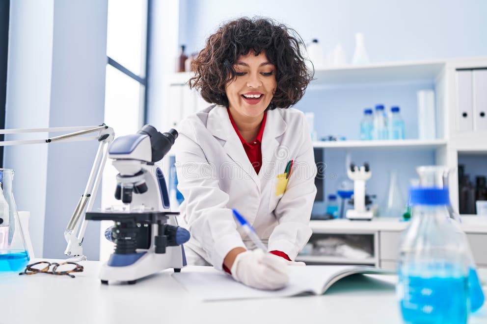 Young Beautiful Hispanic Woman Scientist Using Microscope Writing on ...