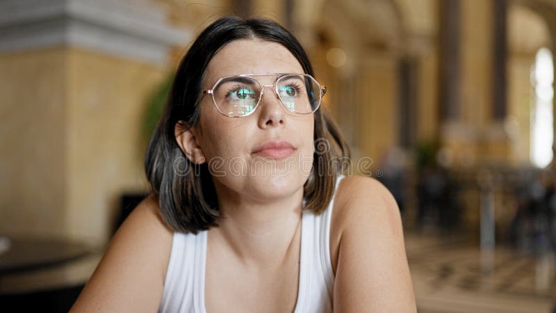 Young Beautiful Hispanic Woman Sitting on the Table Looking Serious at ...