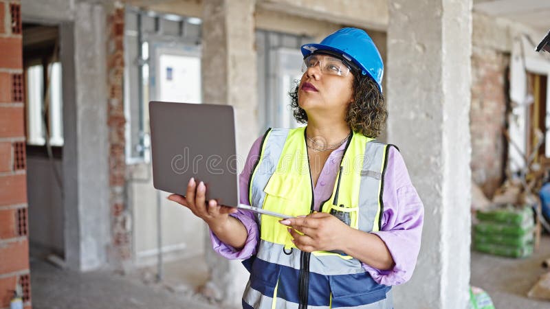 Young Beautiful Latin Woman Builder Using Laptop Looking Around at ...
