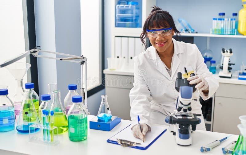 Young Beautiful Latin Woman Scientist Using Microscope Writing Report ...