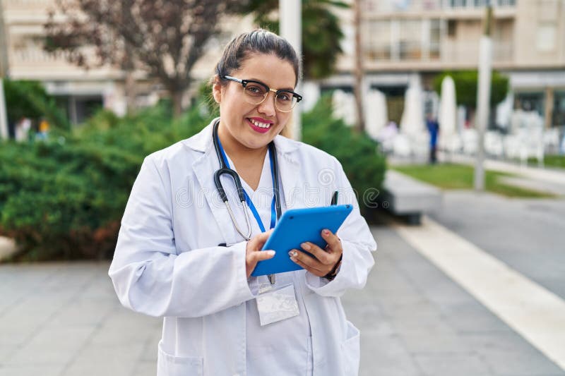 Young Beautiful Plus Size Woman Doctor Smiling Confident Using Touchpad ...