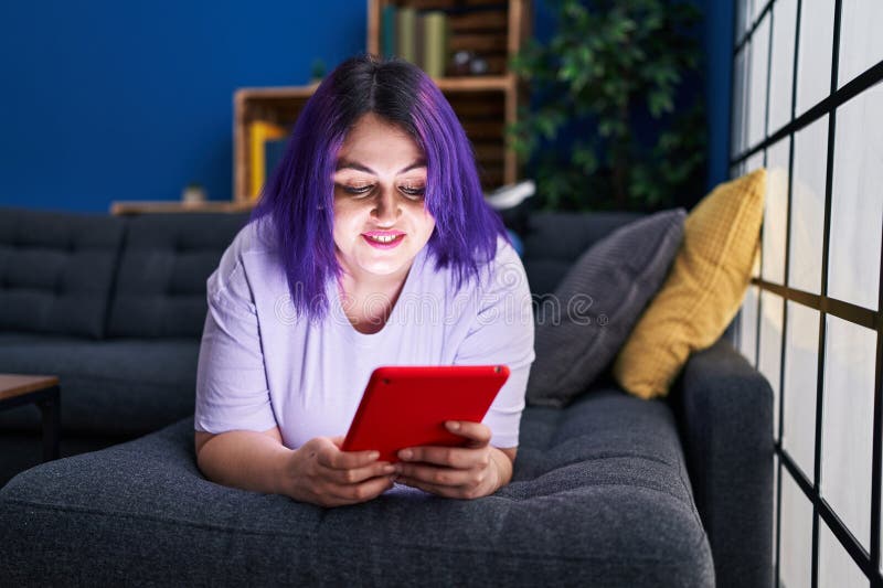 Young Beautiful Plus Size Woman Using Touchpad Lying on Sofa at Home ...