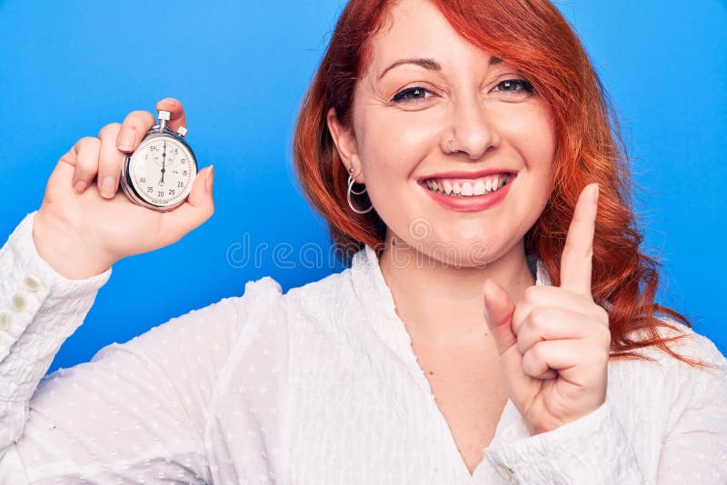Young Beautiful Redhead Woman Doing Countdown Using Stopwatch Over Blue ...