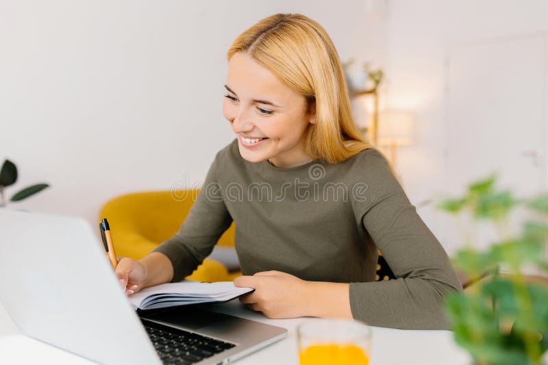 Young Beautiful Student Woman Taking Notes while Using Laptop at Home ...