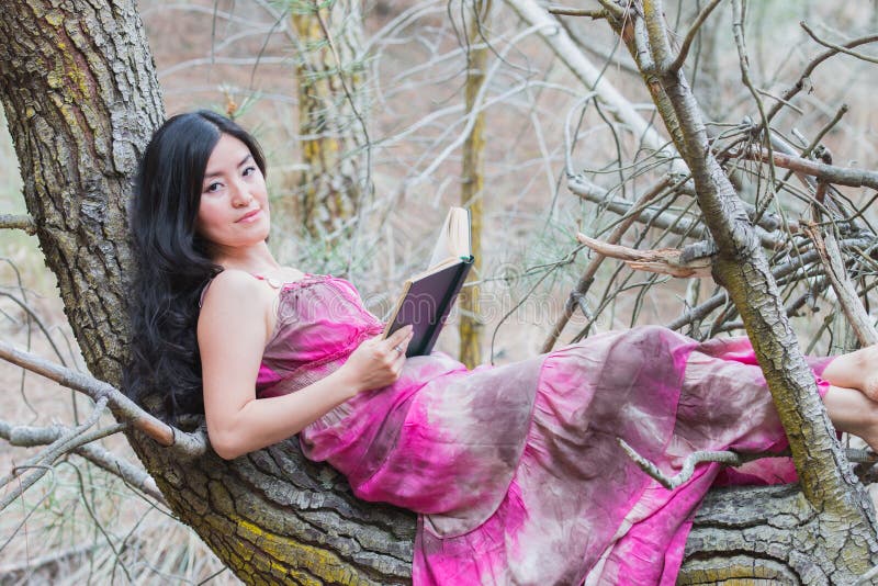 Young Beautiful Woman Lying on a Branch of a Tree with Book Stock Photo ...