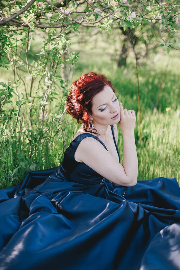 Young Beautiful Woman With Red Hair In A Blue Dress Posing In A