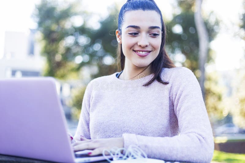 Young Beautiful Woman Sitting Outdoors while Working with Computer ...