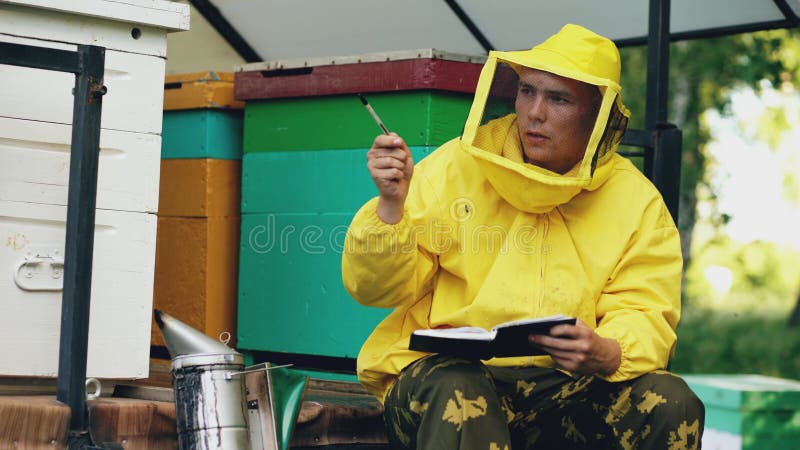 Young Beekeeper Man Write in Notepad Checking Harvest while Sitting ...