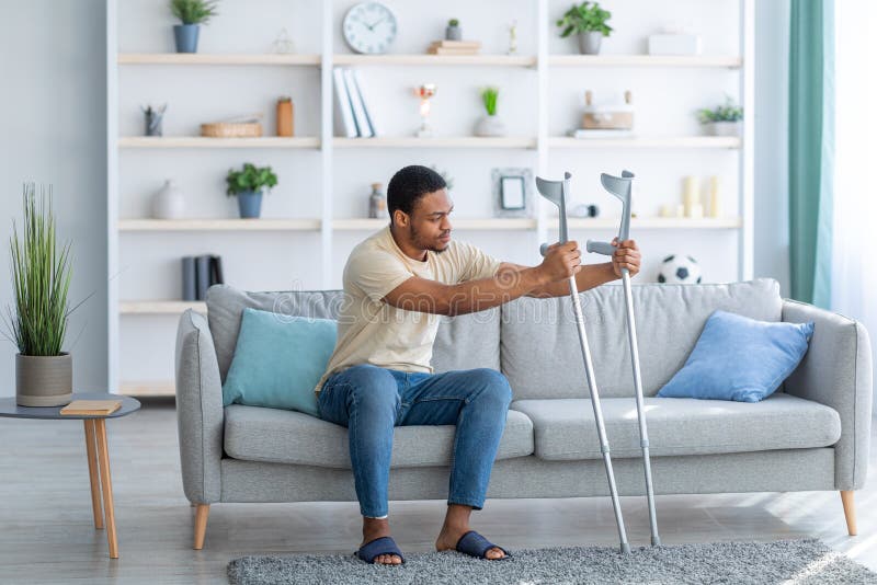 Young Black Guy Having Difficulty Standing Up from Sofa, Leaning on ...