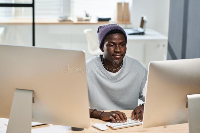 Young Black Man in Casualwear Working Over New Software by Workplace ...