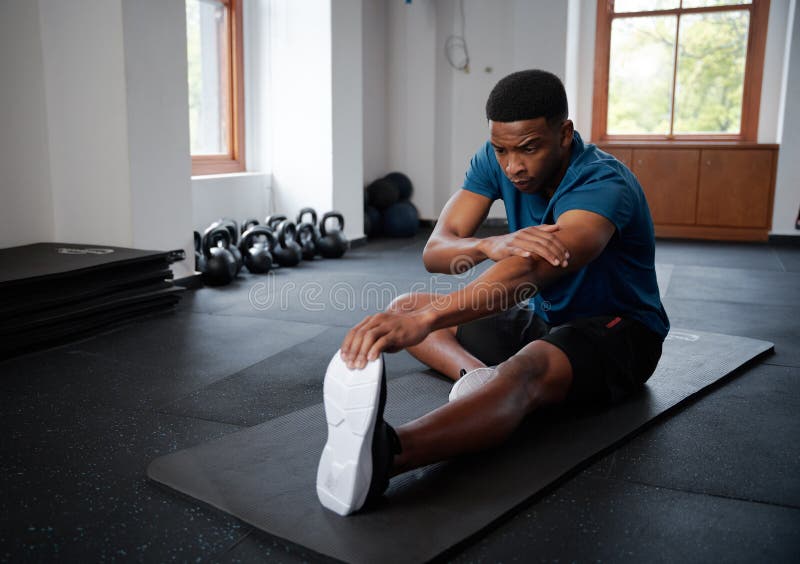 Young Black Man Doing Stretches on Exercise Mat at the Gym Stock Photo ...