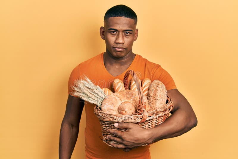 Young Black Man Holding Wicker Basket with Bread Thinking Attitude and ...