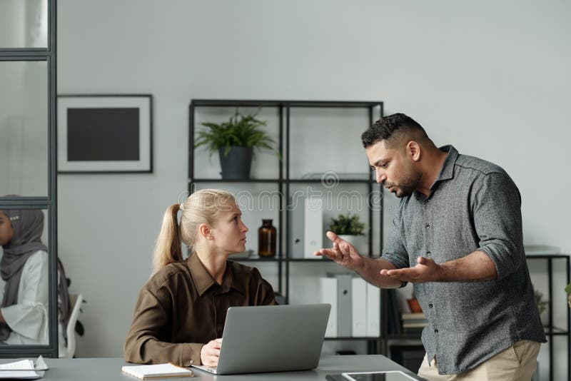Young Blond Businesswoman Looking at Irritated Boss Explaining Working ...
