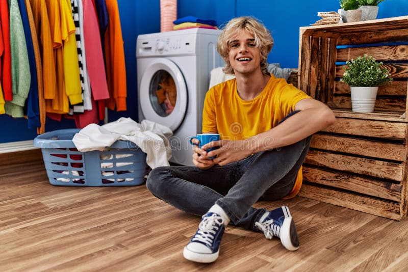 Young Blond Man Drinking Coffee Waiting for Washing Machine at Laundry ...