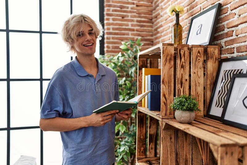 Young Blond Man Reading Book Standing at Home Stock Photo - Image of ...