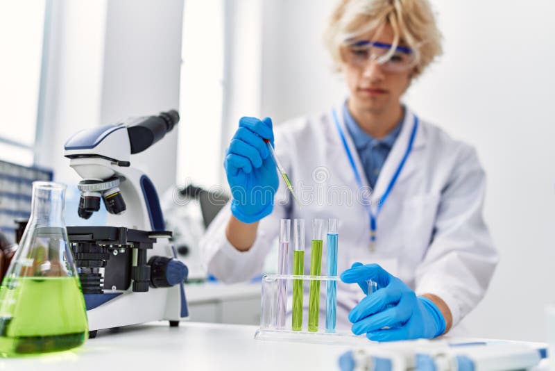 Young Blond Man Scientist Pouring Liquid on Test Tube at Laboratory ...