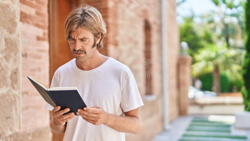 Young Blond Man Smiling Confident Reading Book at Street Stock Photo ...